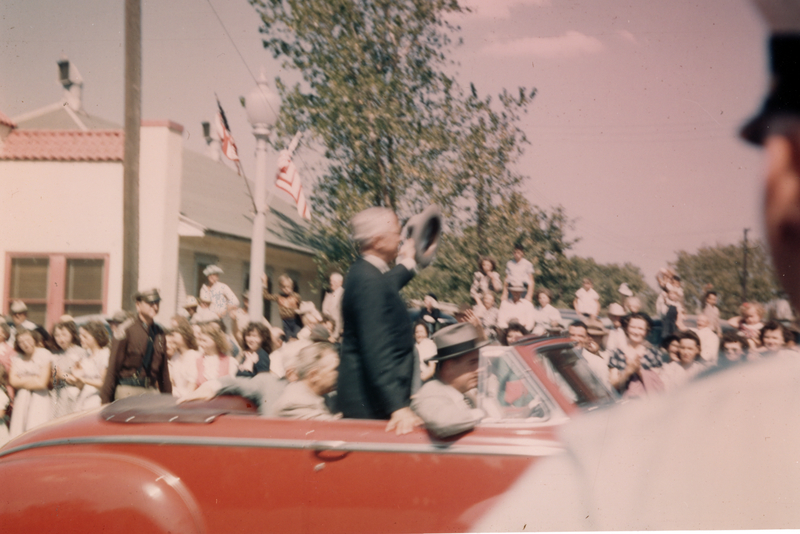 President Truman waves from a red convertible during a motorcade ...