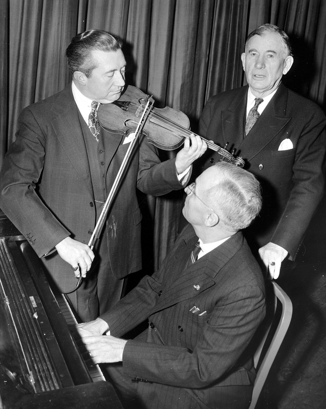 President Truman playing a piano while Vice President Alben Barkley ...