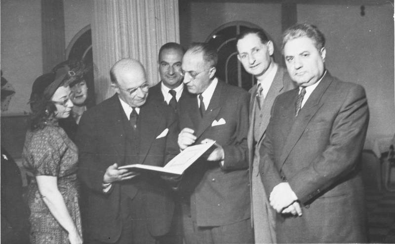 Bluma Jacobson, Eddie Jacobson, and a Group of Men Look at a Book ...