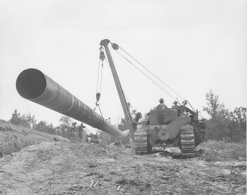 Caterpillar moving a section of pipe | Harry S. Truman