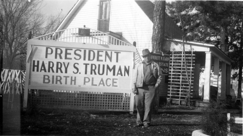 Man pictured with a sign, "President Harry S. Truman Birth Place ...