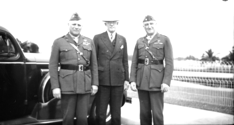 Snapshot of three men standing in front of a car, two in uniform ...